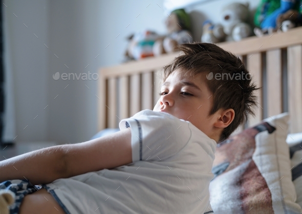 Emotional portrait young boy lying on bed,Sleepy child waking up the ...