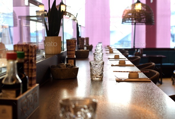 Empty sushi bar place settings with chopsticks and glass. Pink ...
