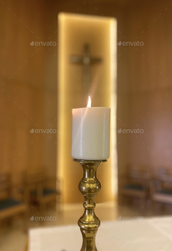 Church worship altar with lighted candle and flame in foreground and ...