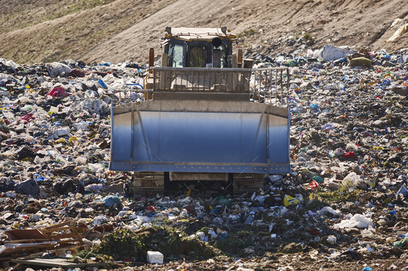 Heavy machinery shredding garbage in an open air landfill. Pullution ...