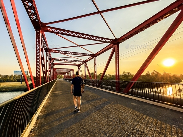A man walking on the red bridge across the Logan River at Beenleigh ...