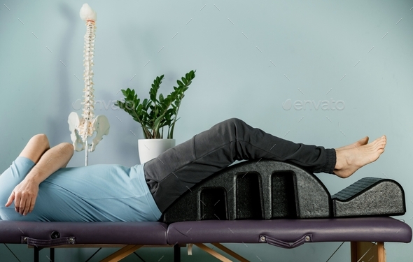 A man lying on the pilates arc in constructive rest postion, si joint ...