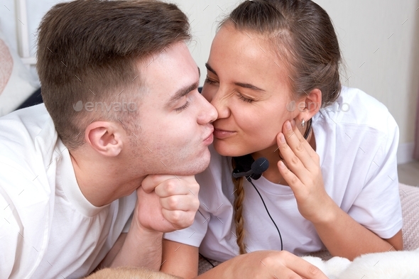 Happy couple kiss each other on the sofa at home in the living room ...