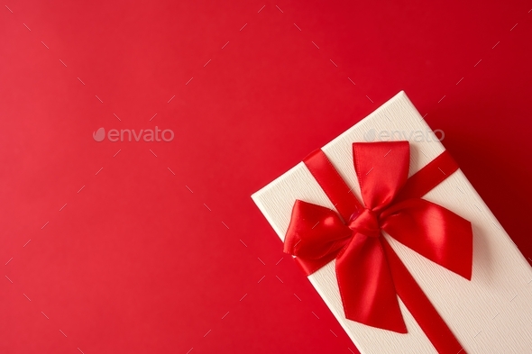 White present with red ribbon on the bright red background . Festive ...