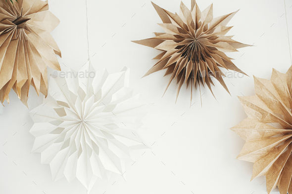 Stylish paper christmas stars hanging on white wall background. Modern ...