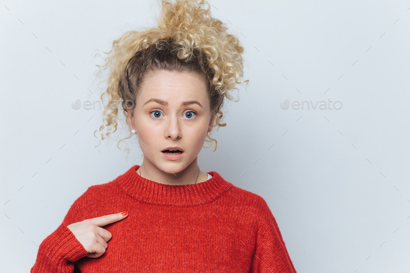 Shocked stunned young woman with surprised expression, indicates at ...