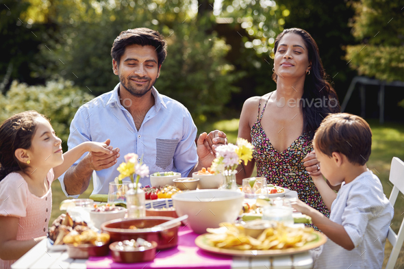 Religious Family Saying Prayers Or Grace Before Eating Outdoor Meal In ...