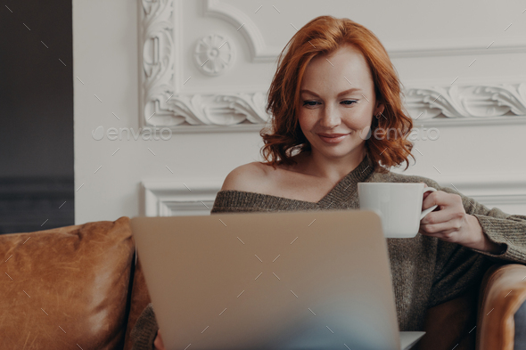 woman concentrated in laptop computer, ponders on completing working ...