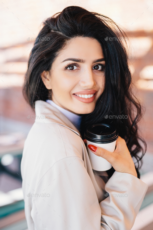 Cheerful female with dark hair lovely appearnce holding takeaway coffee ...