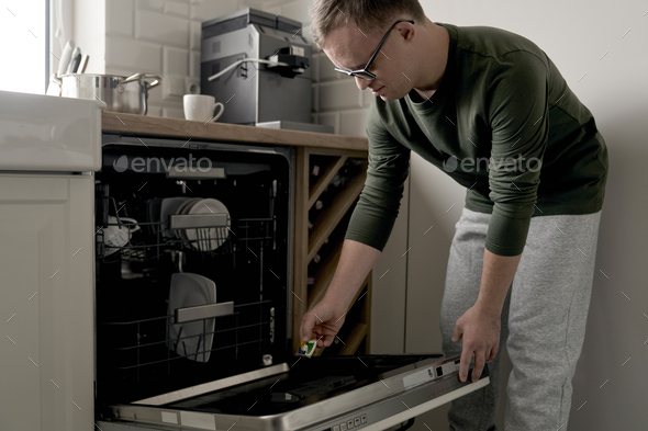 Adult man with down syndrome uploading dish washer at home Stock Photo ...