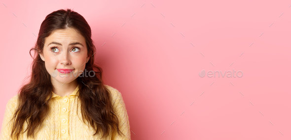 Close up portrait of modest cute girl, smiling and looking shy at upper ...