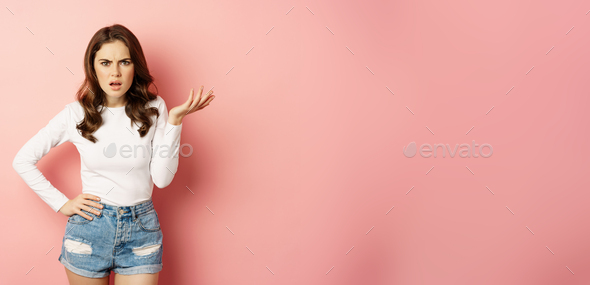 Confused glam girl looking frustrated, raising hand in puzzled gesture ...