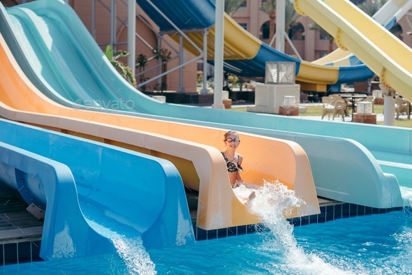 girl rides a water slide in a water park Stock Photo by Yuliya_Kokosha