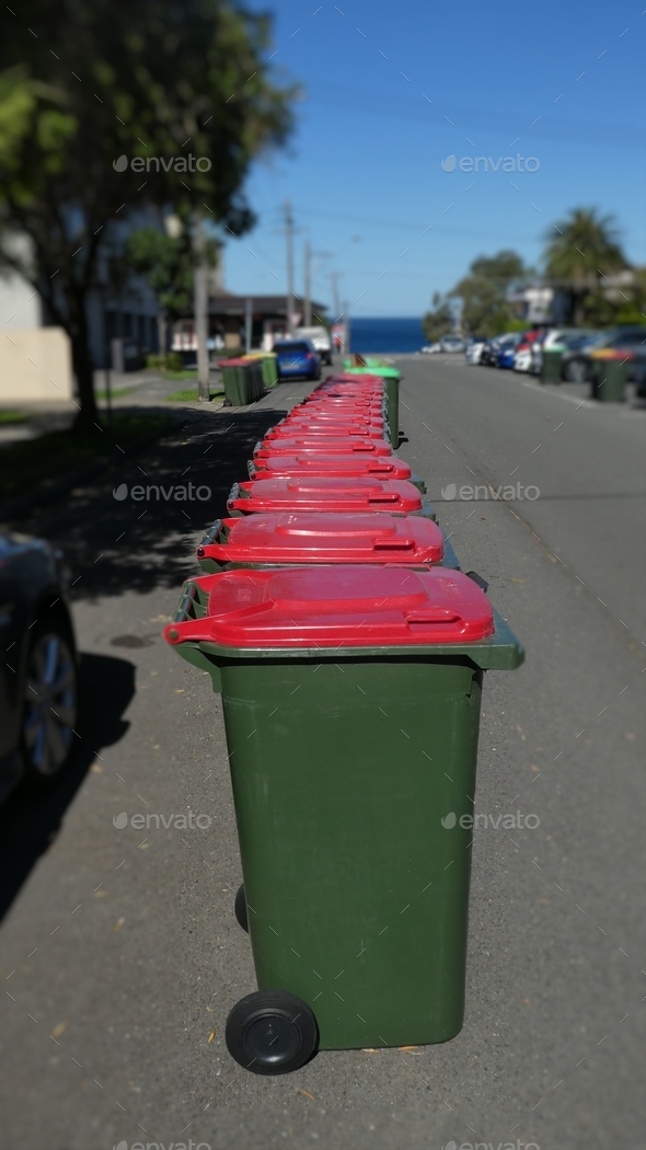 plastic garbage bins in a row out on the street ready for collection ...