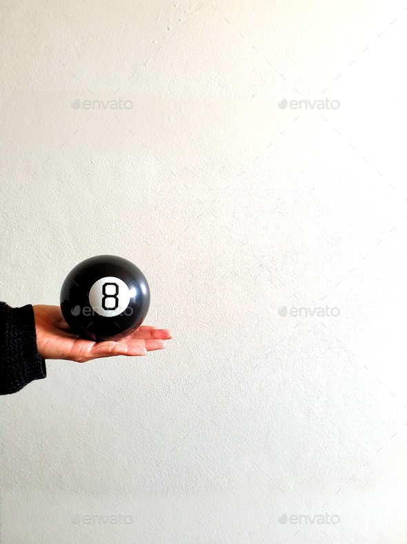 Side view of hand holding eight ball minimal style against white ...