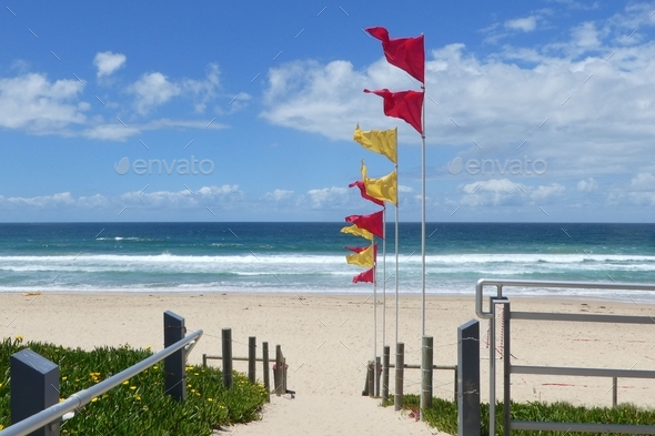 Red and yellow flags at the beach path leading towards water Stock ...