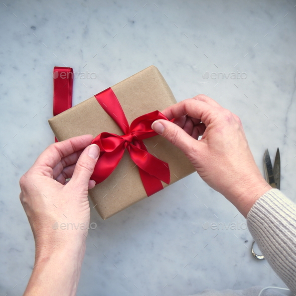 Tying a bow, wrapping a present with red ribbon Stock Photo by ehpyle