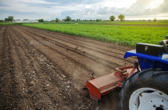 A tractor with a milling machine is cultivating a farm field. Stock ...