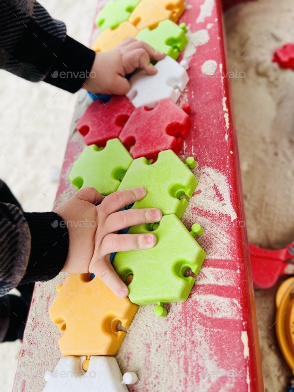 The child plays in the sandbox with colorful puzzles. Stock Photo by ...