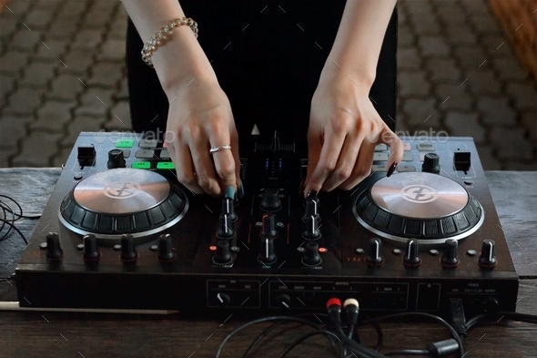 Dj woman with mixing console, female hands turning sound of clubbing ...
