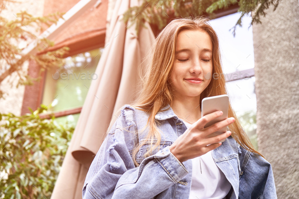 Pretty girl outdoors. Caucasian real people using mobile phone Stock Photo by elenavolf