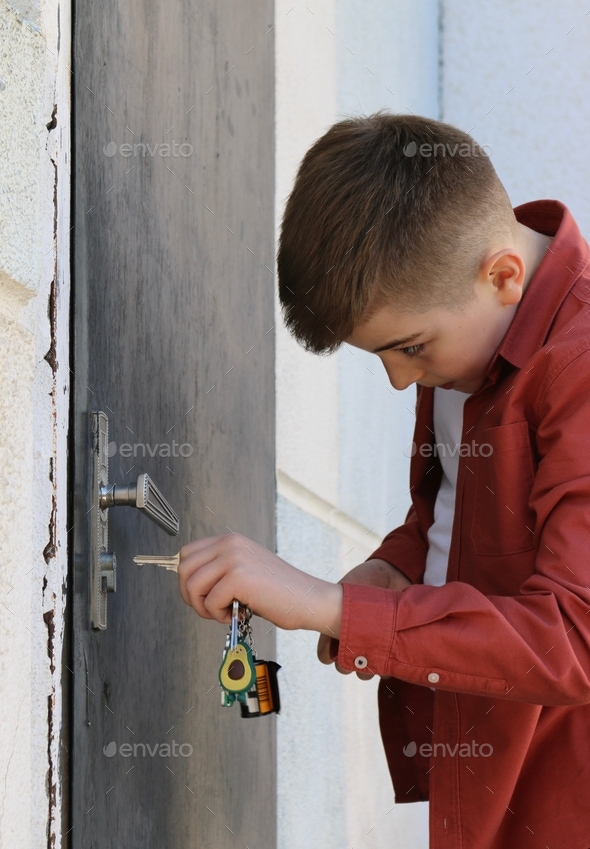 A blond little boy in a shirt opens the door with keys Stock Photo by ...