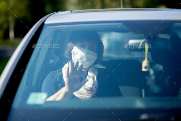 Elderly senior woman wearing a face mask while driving a car during ...