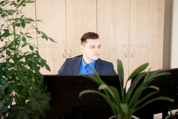 Male receptionist wearing blue business suit types on his computer at ...