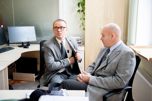 Two serious businessmen speaking and working at the office Stock Photo ...