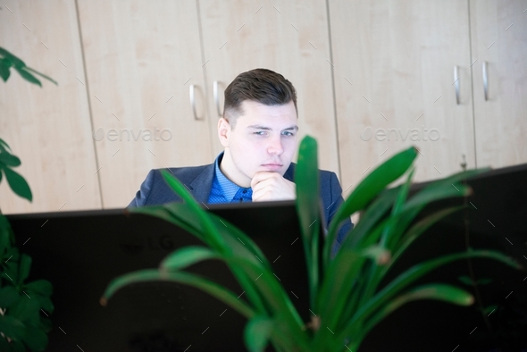 Male receptionist wearing blue business suit types on his computer at ...
