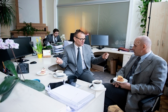 Colleagues having a coffee break in the office at their work desk Stock ...