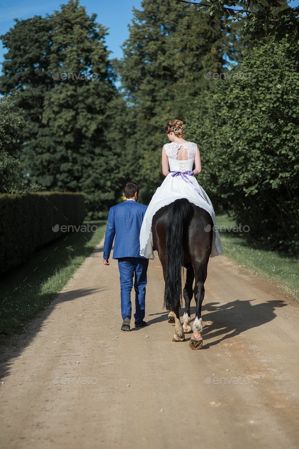 The beautiful attractive bride is ridding the horse while her lover is ...