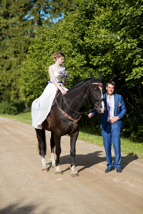 The beautiful attractive bride is ridding the horse while her lover is ...