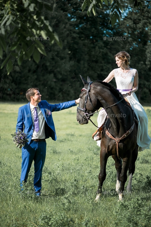 The beautiful attractive bride is ridding the horse while her lover is ...