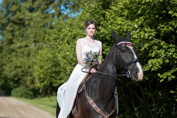 Beautiful and stunning bride, riding a horse in the nature, on her ...