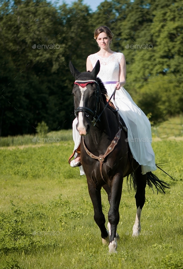 Beautiful and stunning bride, riding a horse in the nature, on her ...