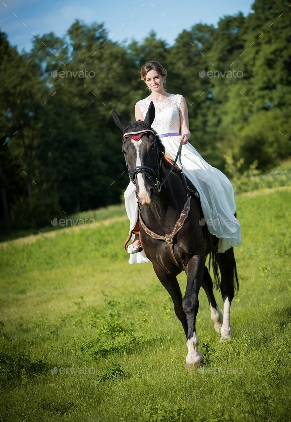 Beautiful and stunning bride, riding a horse in the nature, on her ...