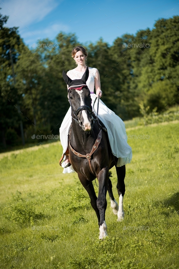 Beautiful and stunning bride, riding a horse in the nature, on her ...