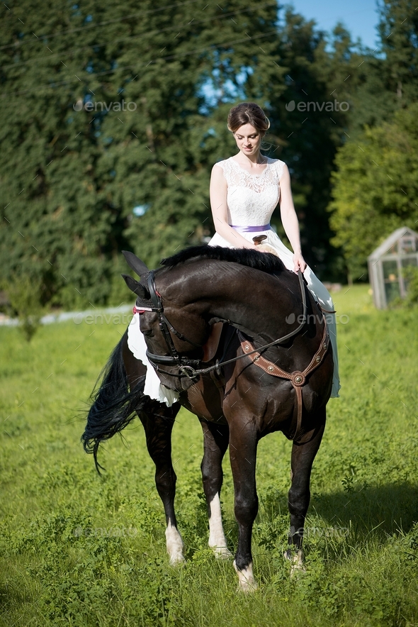 Beautiful and stunning bride, riding a horse in the nature, on her ...