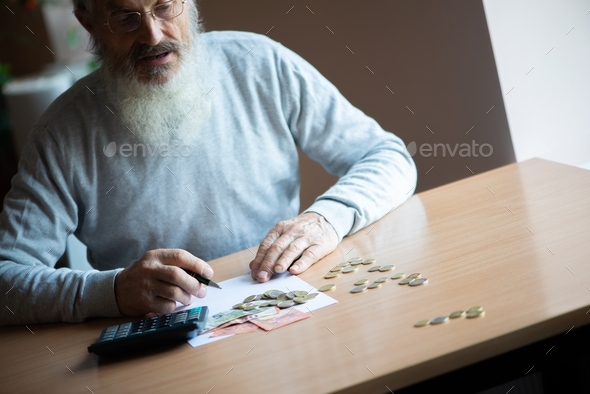 Old bearded senior man with calculator and bills counting euro money ...
