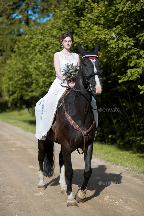Beautiful and stunning bride, riding a horse in the nature, on her ...