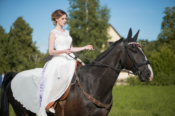 Beautiful and stunning bride, riding a horse in the nature, on her ...