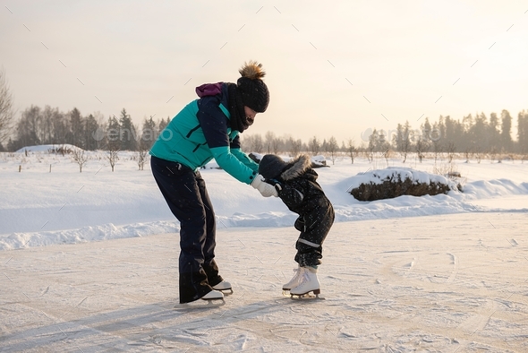 Young mother teaching her little baby boy son ice skating at outdoor ...