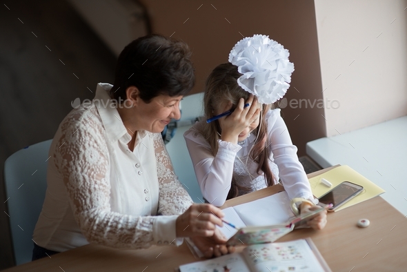 Teacher helping student little girl find the right answer during class ...