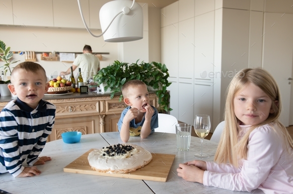 Three children sitting at family dinner table at home Stock Photo by zelmab