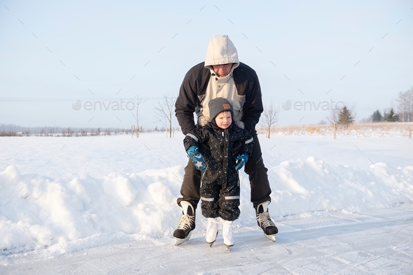 Grandfather teaching her little grandson ice skating at outdoor skating ...