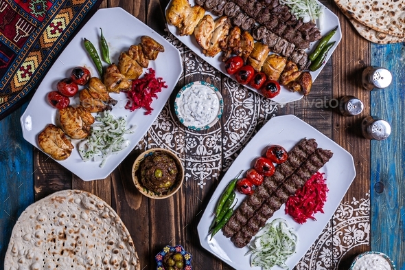 Flat lay Persian table with a mix of kebabs, traditional bread, and ...