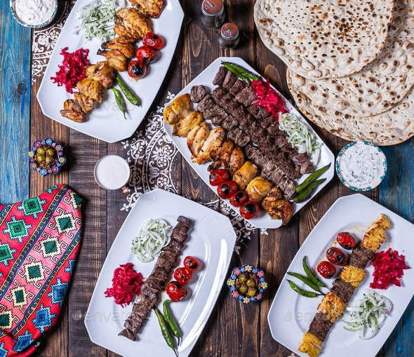 Flat lay Persian table with a mix of kebabs, traditional bread, and ...