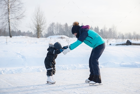 Young mother teaching her little baby boy son ice skating at outdoor ...