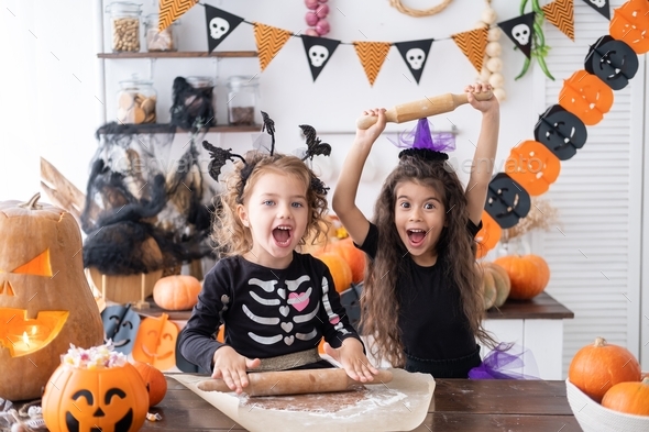 two kids girl in costume of witch, baking cookies, having fun in ...